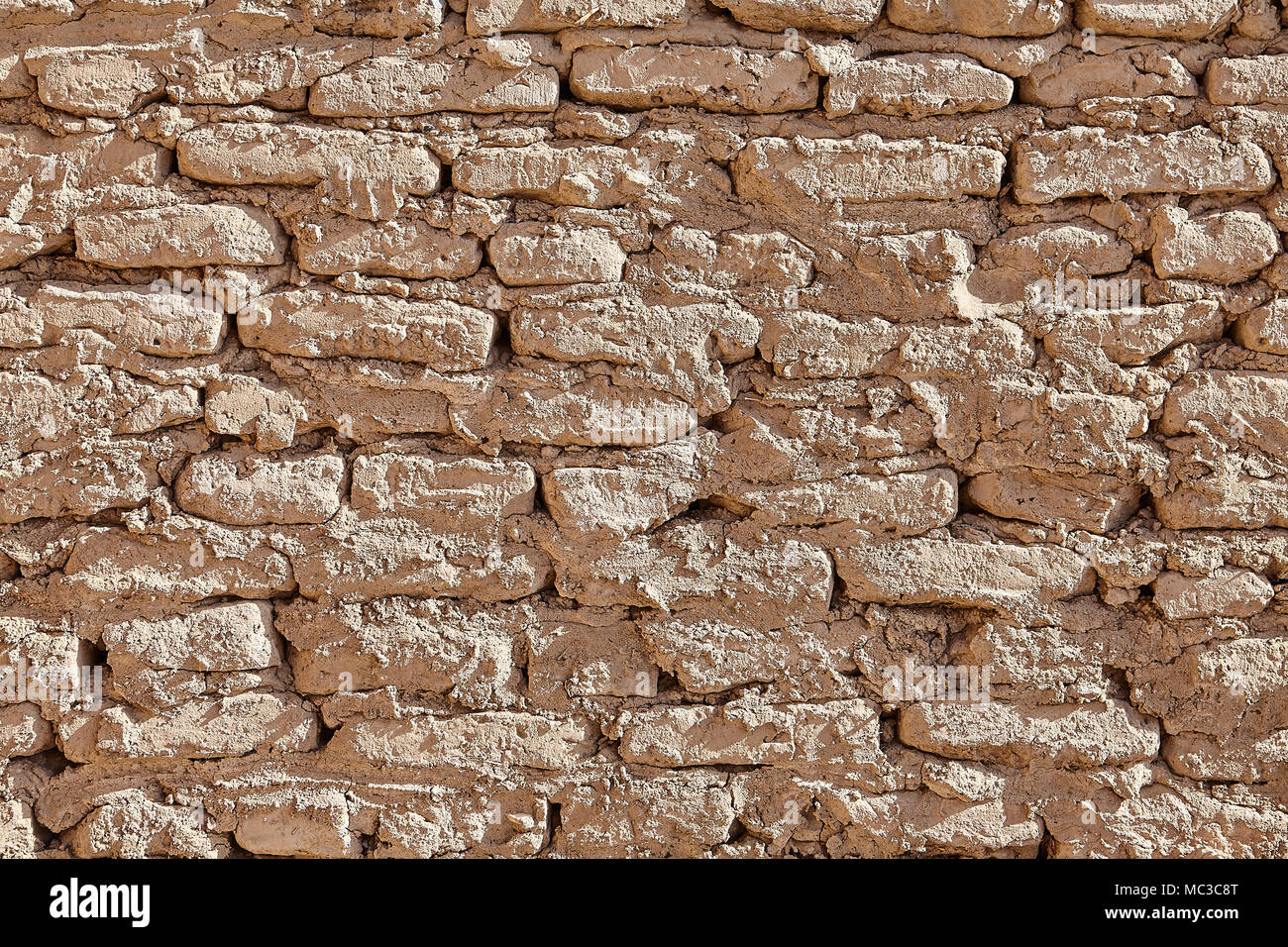 Wall fence of formless clay bricks, background texture Stock Photo - Alamy