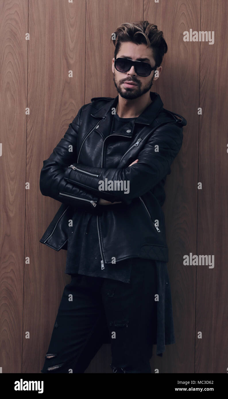 image of a fashion side man stands with crossed hands on a wooden ...