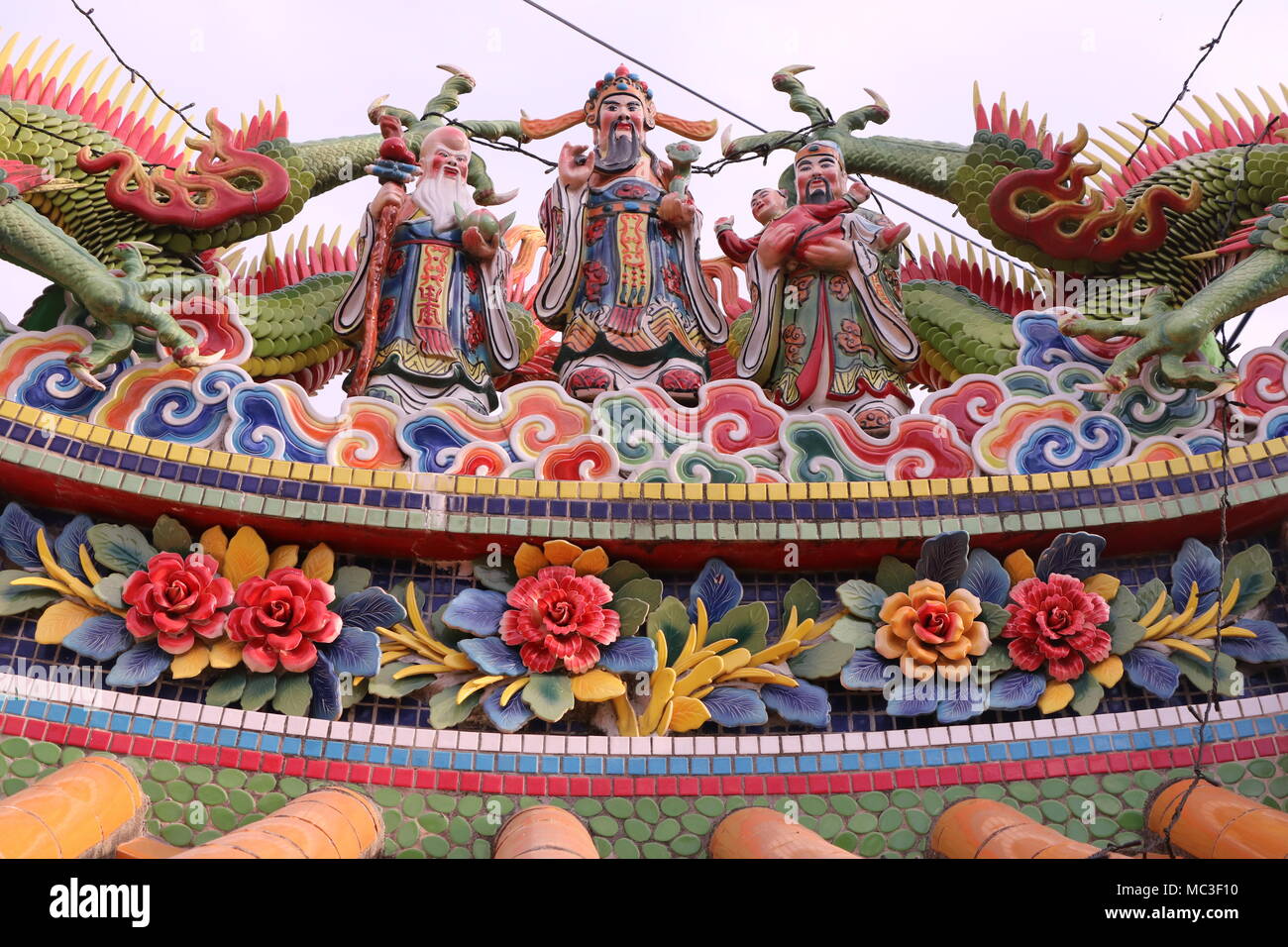 Ceramic statue on rooftop of three Chinese traditional Gods and flower ...