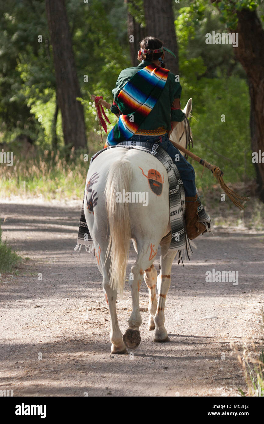 Warrior in Comanche clothing riding white horse along a trail through ...
