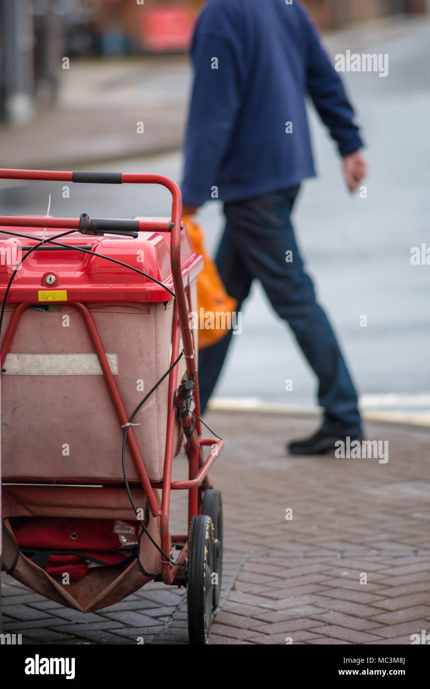 bright red royal mail push trolley barrow chained to cast iron fence ...