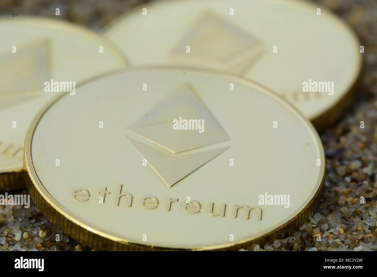 Ethereum coin close up on the beach, golden color Stock Photo - Alamy