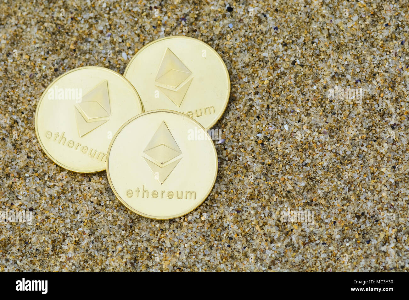 Ethereum coin close up on the beach, golden color Stock Photo - Alamy