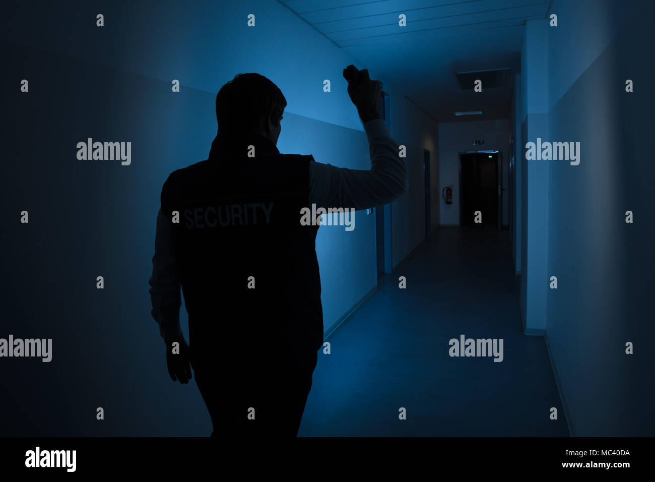 Rear View Of A Security Guard Standing In Corridor Of The Building ...