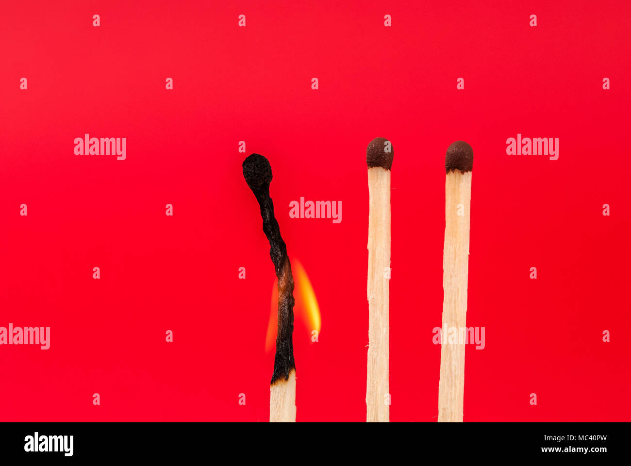 Three matches and one burned on red background Stock Photo - Alamy