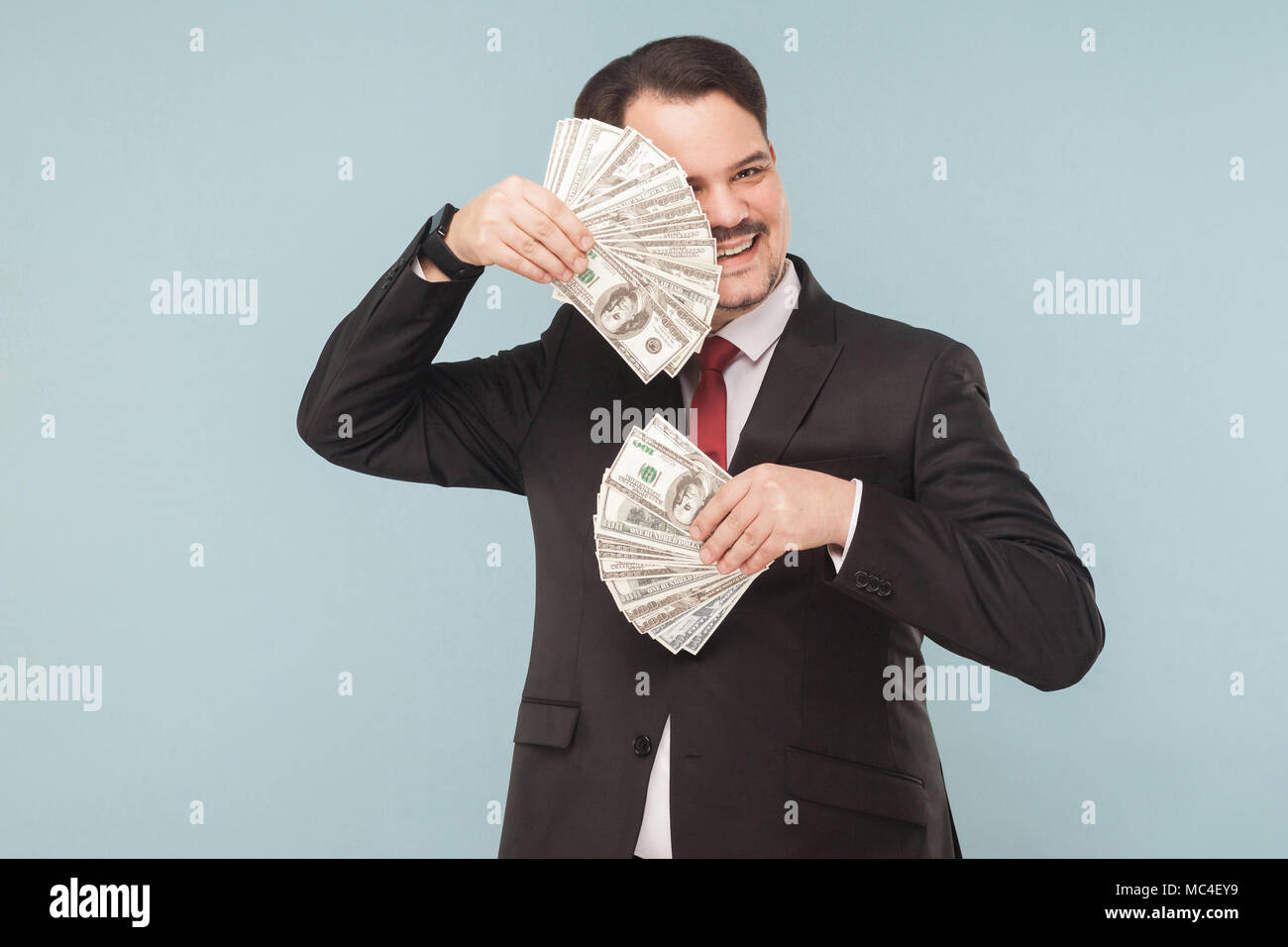 Businessman hides behind fans out of money. Indoor, studio shot ...