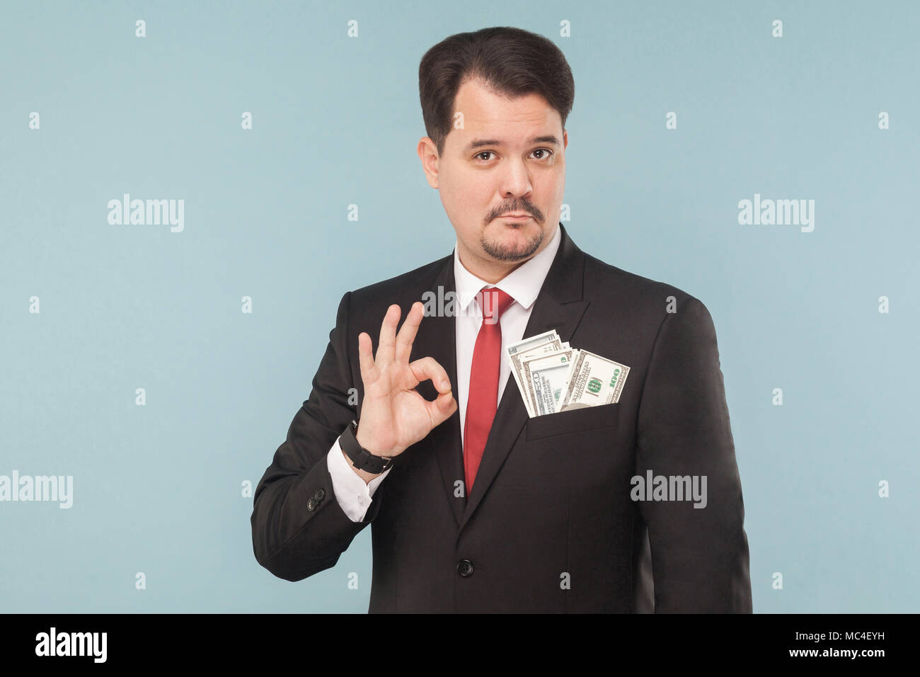Businessman pointing finger at money in the pocket, ok sign. Indoor ...