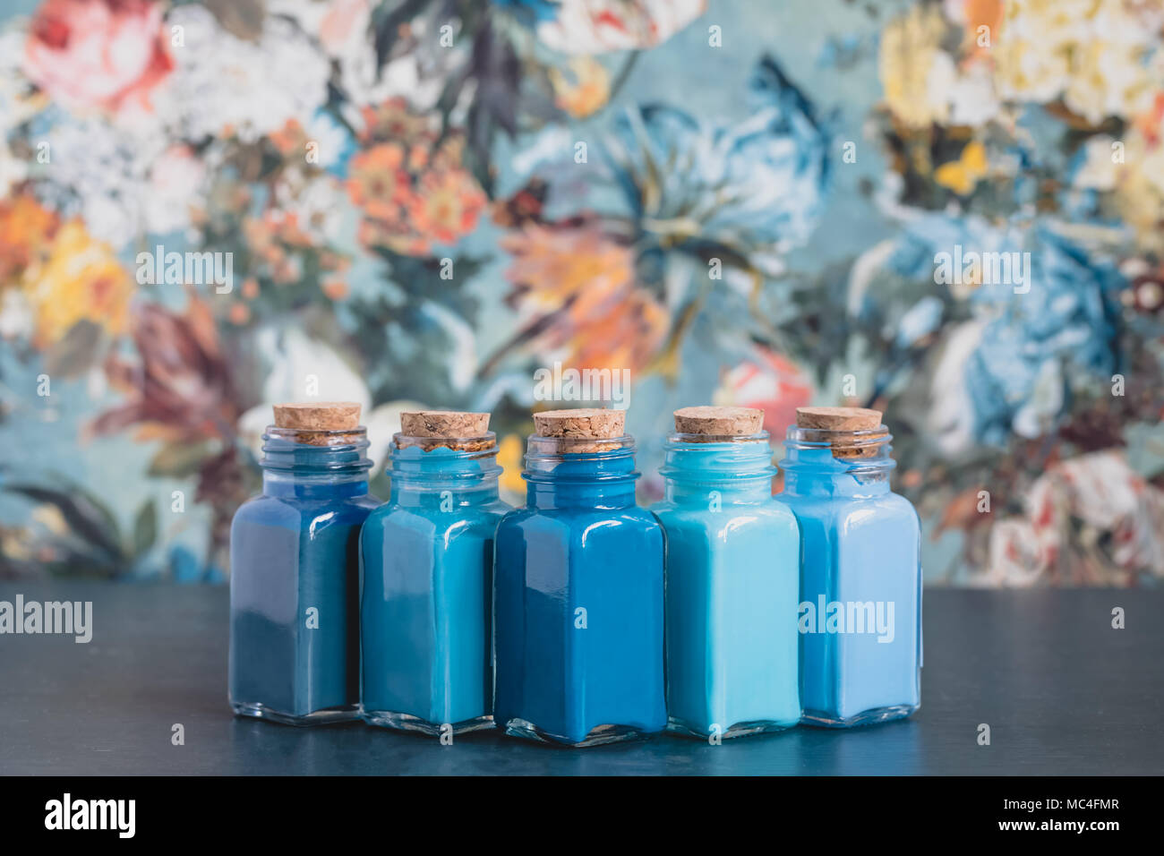 Colorful bottles with blue shades paints on wallpaper background ...