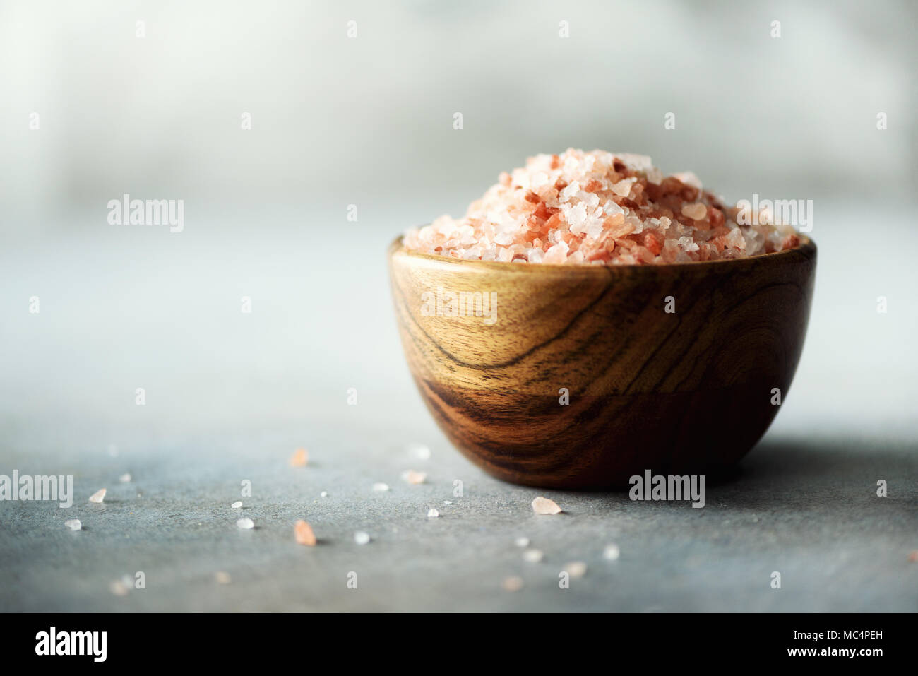 Pink Himalayan salt crystals and powder in wooden bowls on grey ...