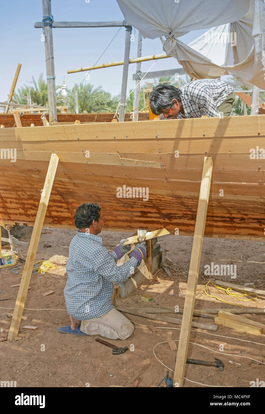 Unidentified workmen building a traditional wooden dhow at the Dhow ...