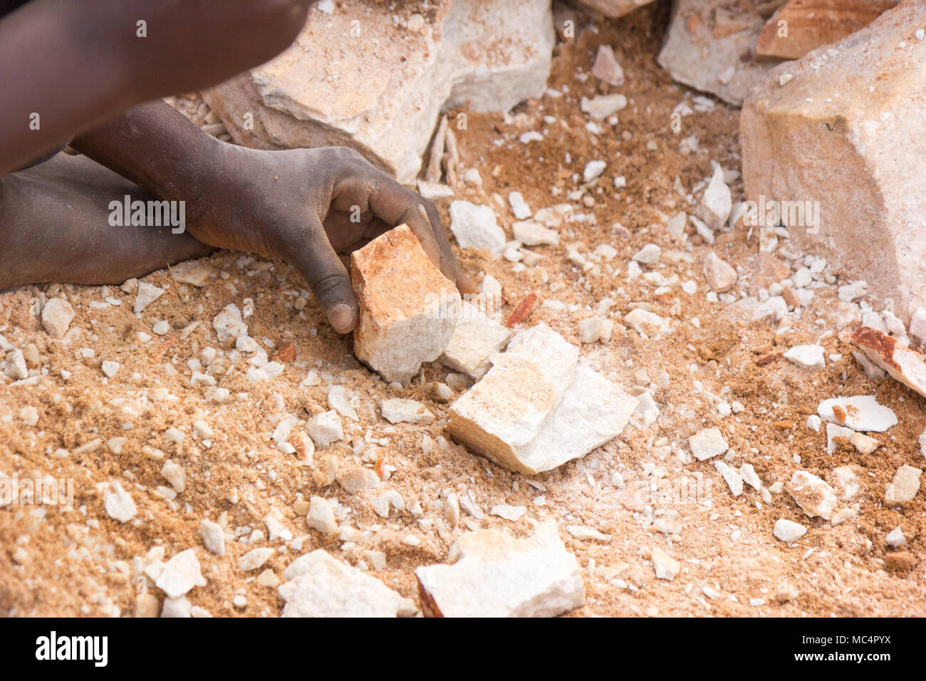 Ugandan child's hands breaking rocks into small slabs for his or her ...