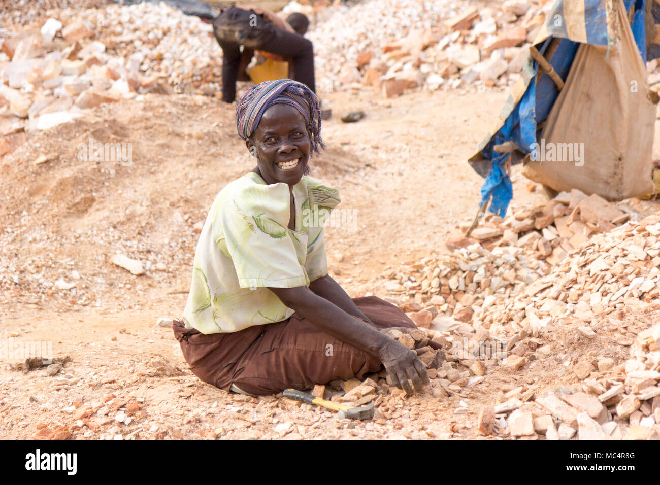 Lugazi, Uganda. June 18 2017. A Ugandan woman breaking rocks into small ...