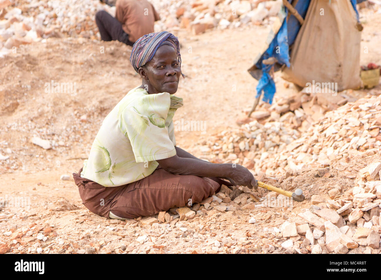 Lugazi, Uganda. June 18 2017. A Ugandan woman breaking rocks into small ...