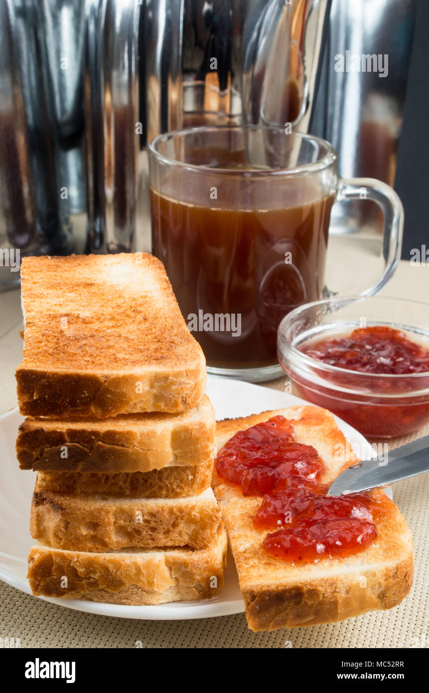 Fried toasts with strawberry jam on the table with kitchen utensils ...