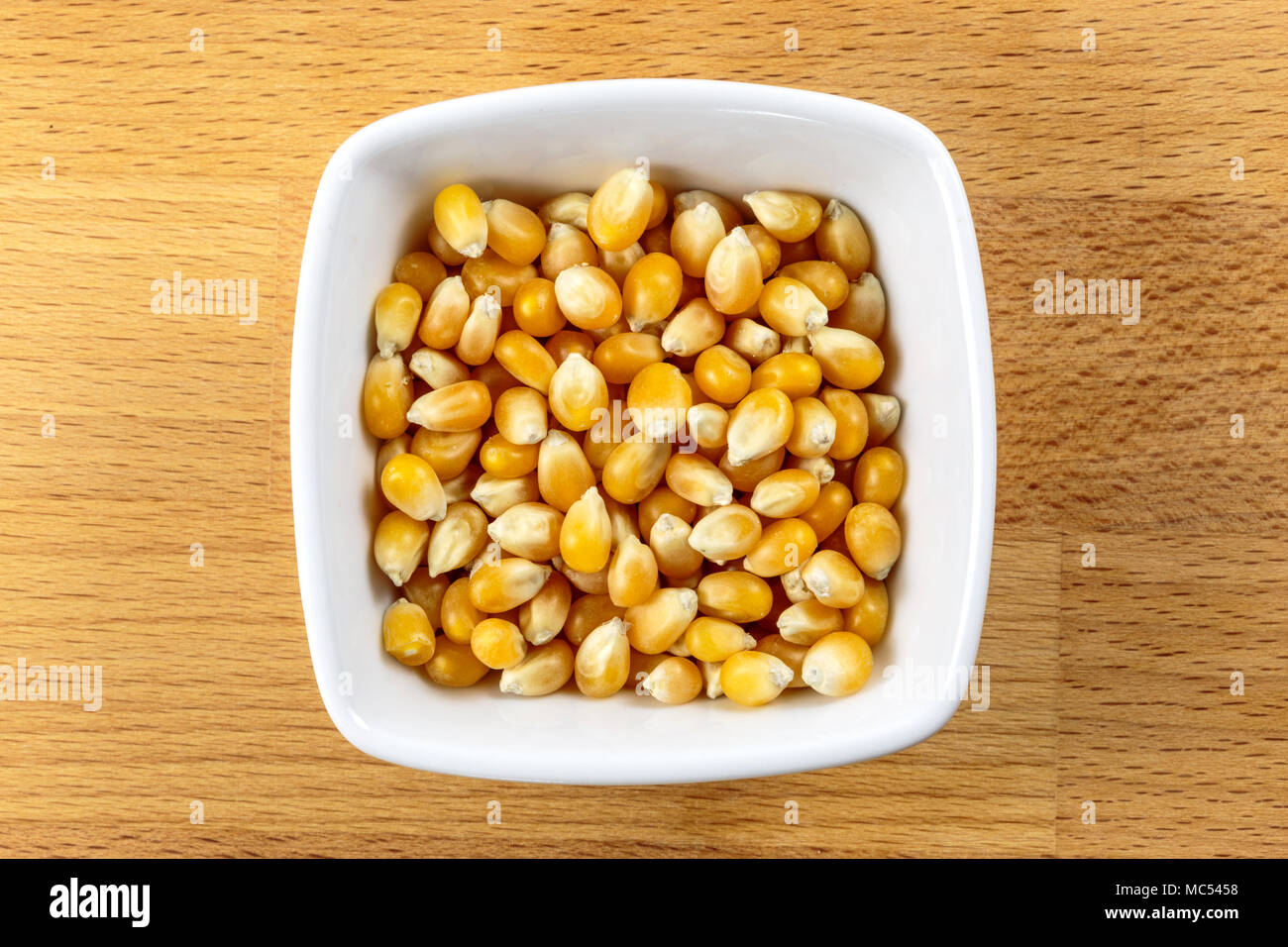 Overhead shot of raw popping corn, or popcorn, in a white bowl on a ...