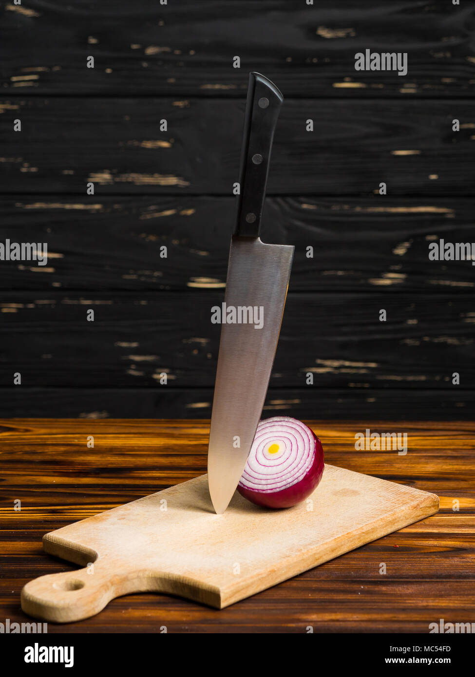 large chef knife sticks out from wooden cutting board om black shabby ...