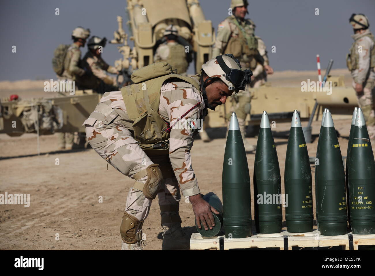 An Iraqi army soldier picks up a round for an M198 155 mm howitzer as ...