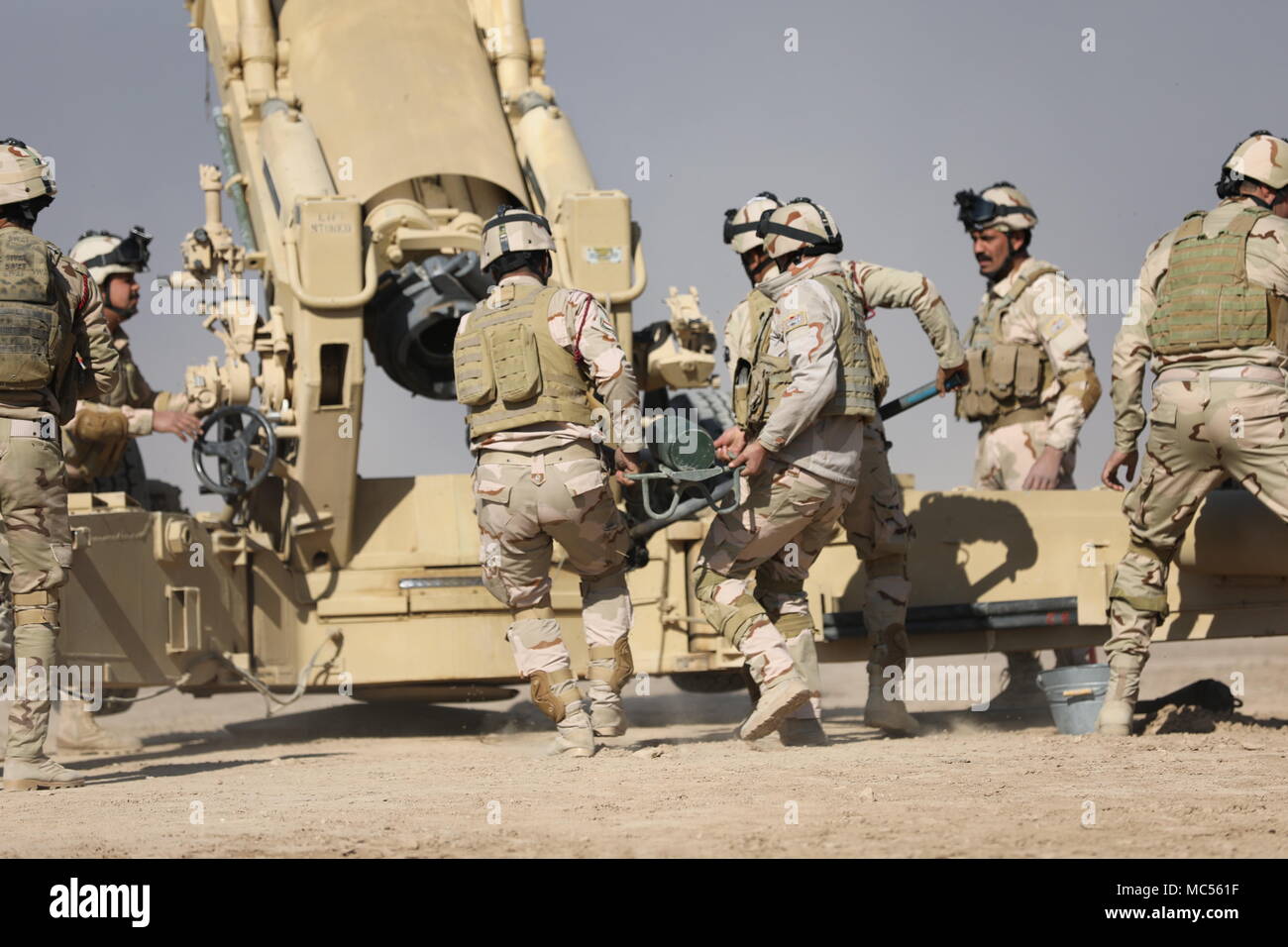 Iraqi army soldiers load a M198 155 mm howitzer while being trained by ...