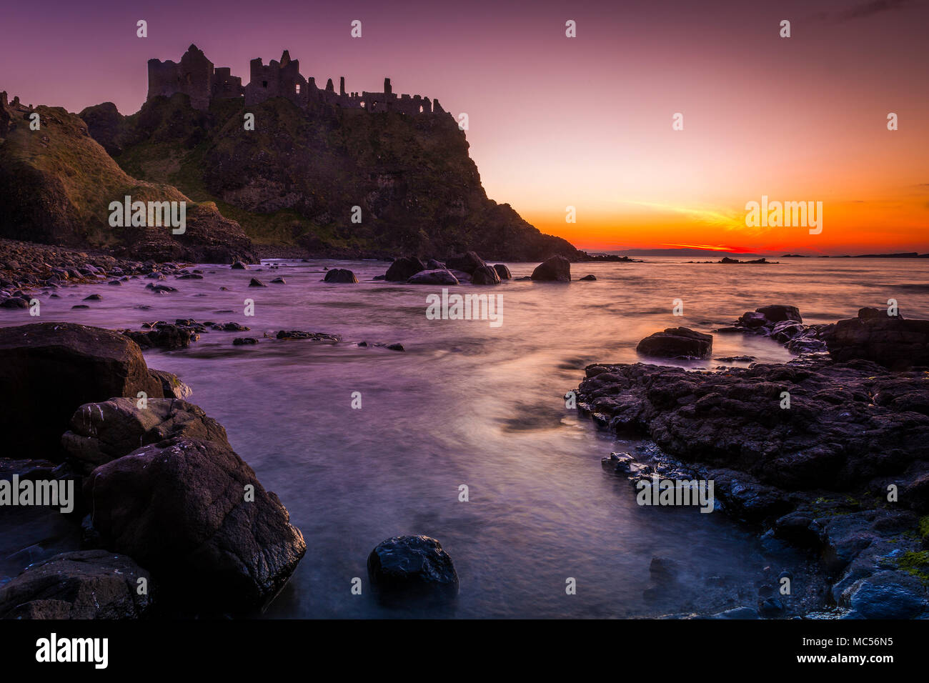Dunluce Castle after sunset with the sea swirling around the foreshore ...