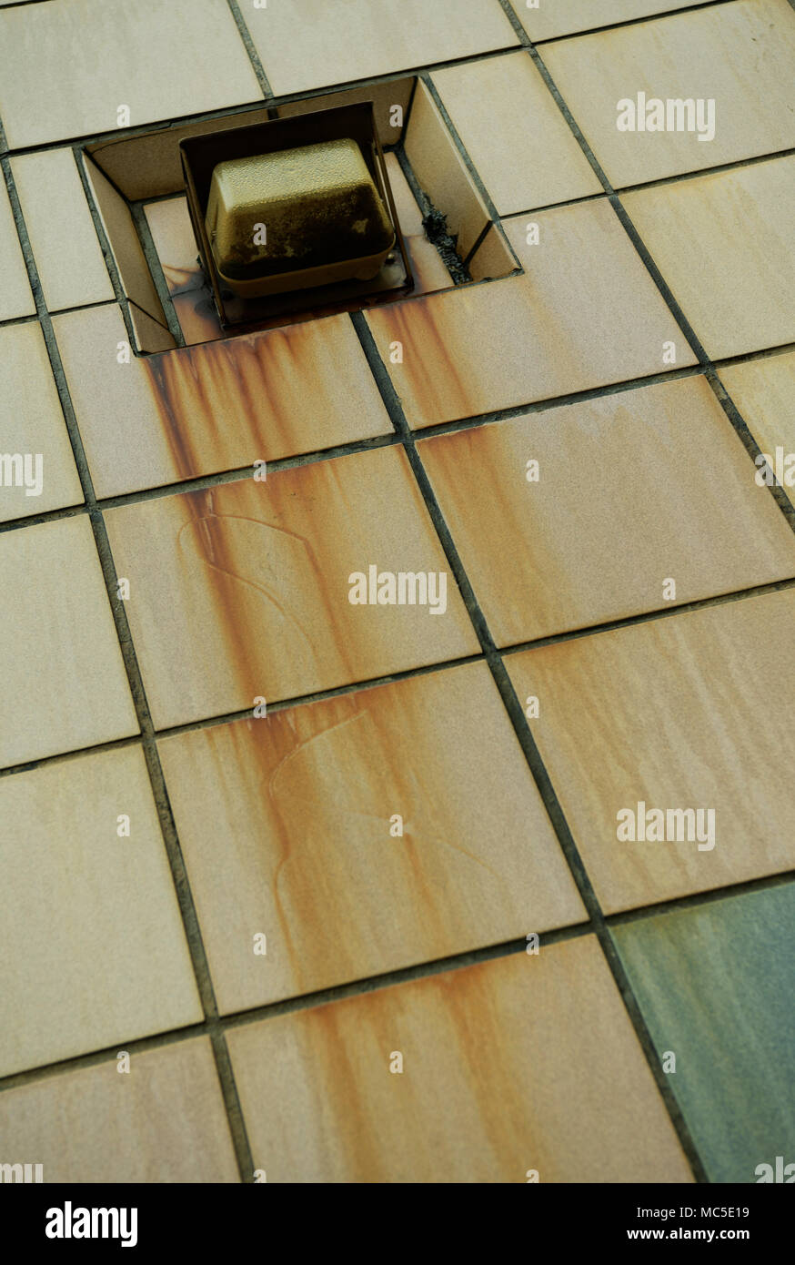 Brown rust marks in streaks running down exposed tiled wall showing ...