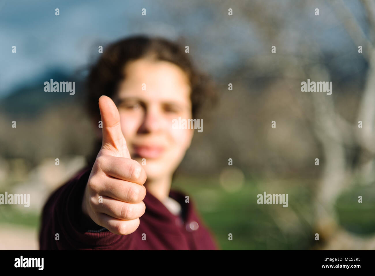 Beautiful young adult woman doing thumbs up gesture. Focus on hand ...