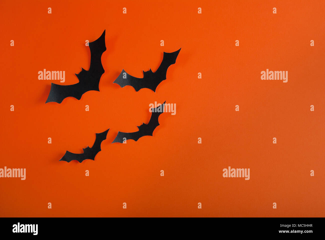 Four bats shape flying on orange background with space for design ...