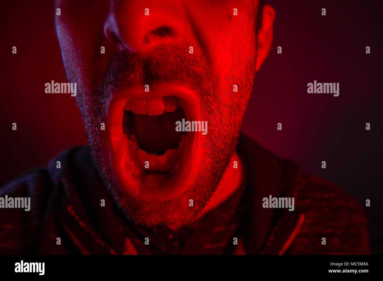 Man with angry facial expression screaming out loud. Close up portrait ...