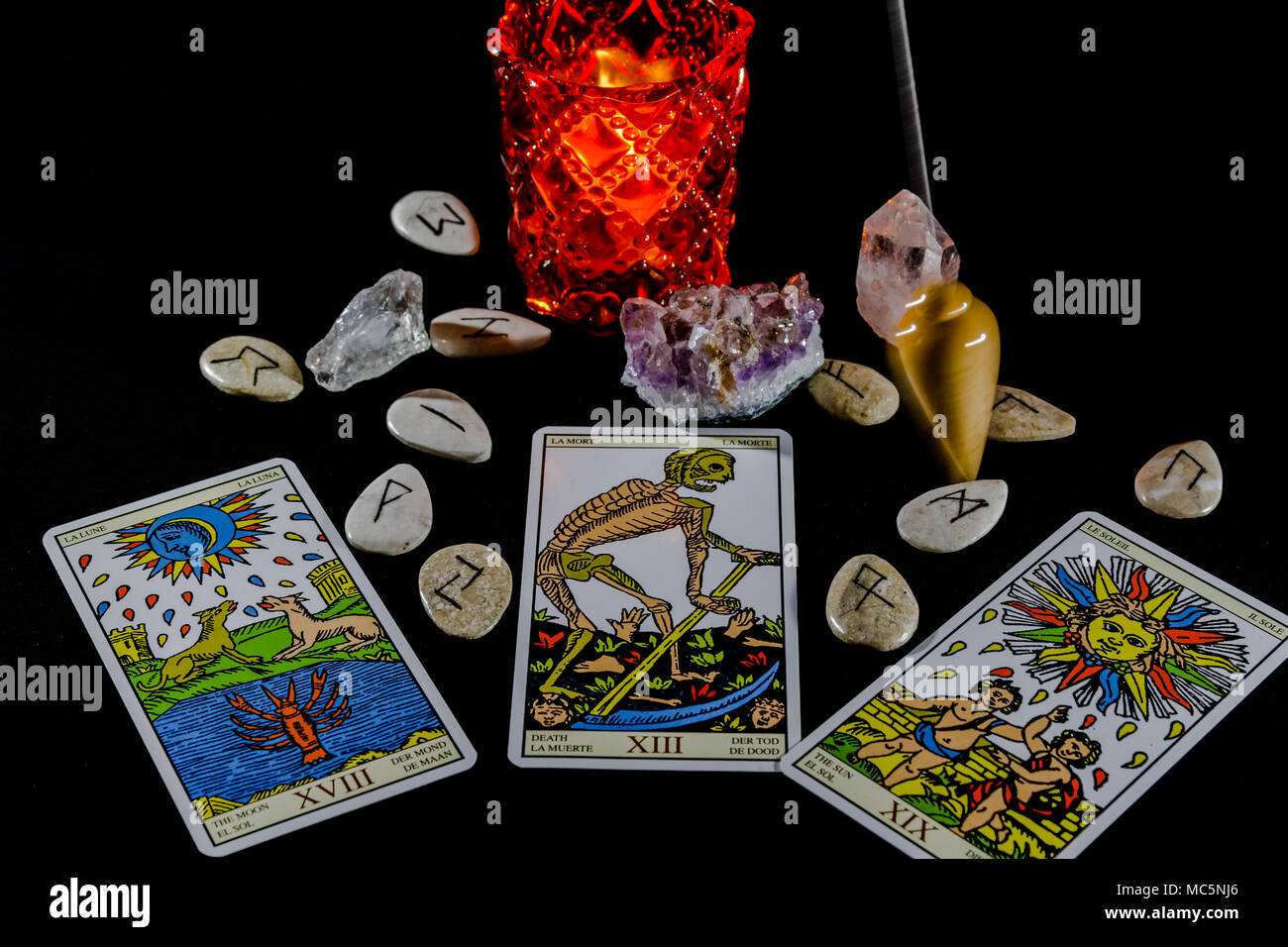 Pendulum swinging above runes, crystals & tarot cards Stock Photo - Alamy