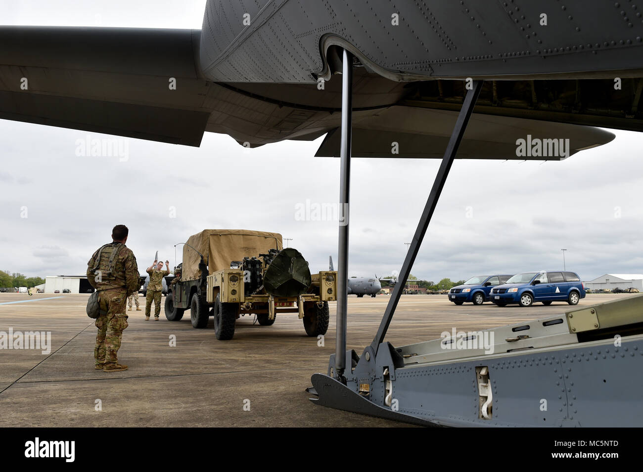 A loadmaster directs the positioning of a Humvee onto a C-130 Hercules ...