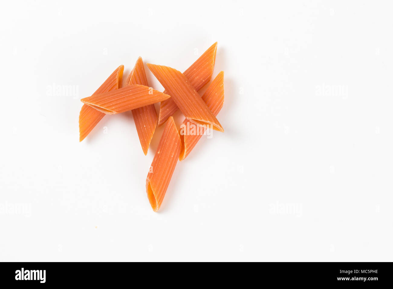 raw orange coloured pasta penne with tomato flavour on white background ...