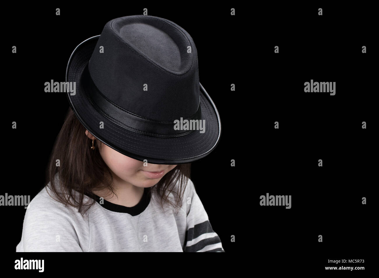 girl in cap with head tilted on black background Stock Photo - Alamy