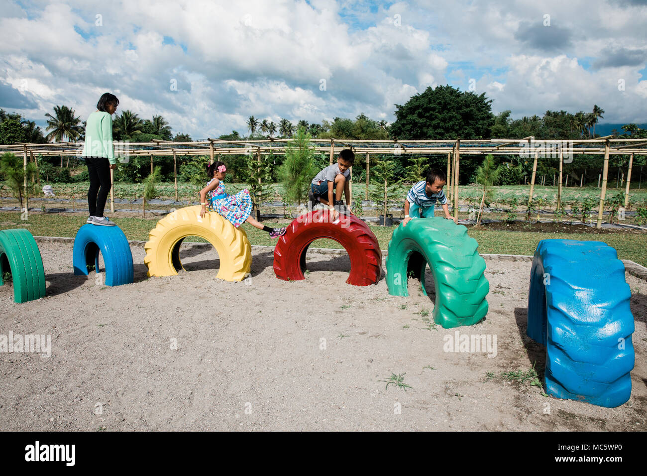 Children playing in board daylight, hopping in colorful tires Stock ...