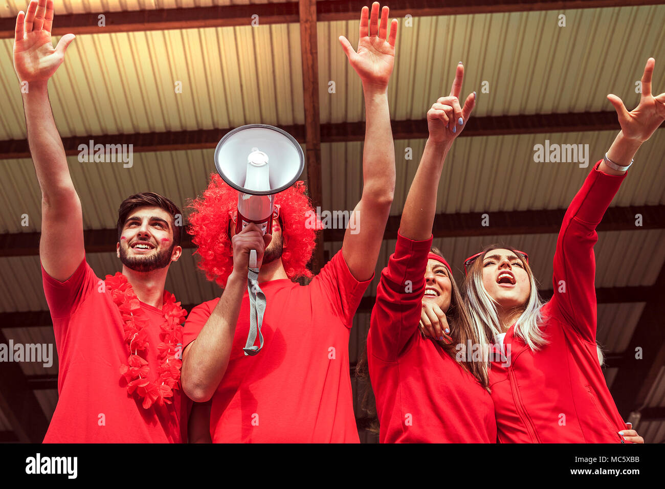 group of fans dressed in red color watching a sports event in the ...