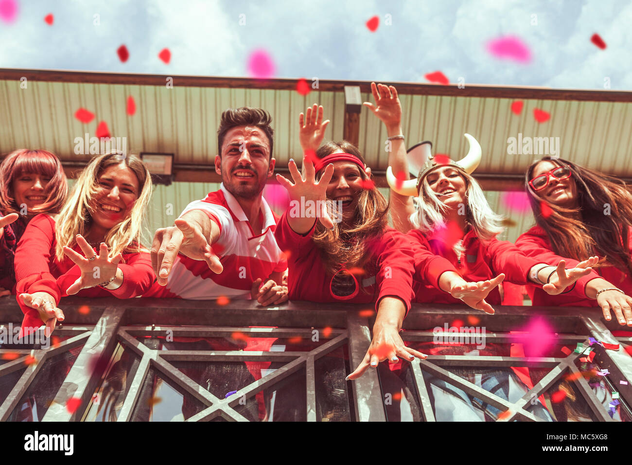 group of fans dressed in red color watching a sports event in the ...