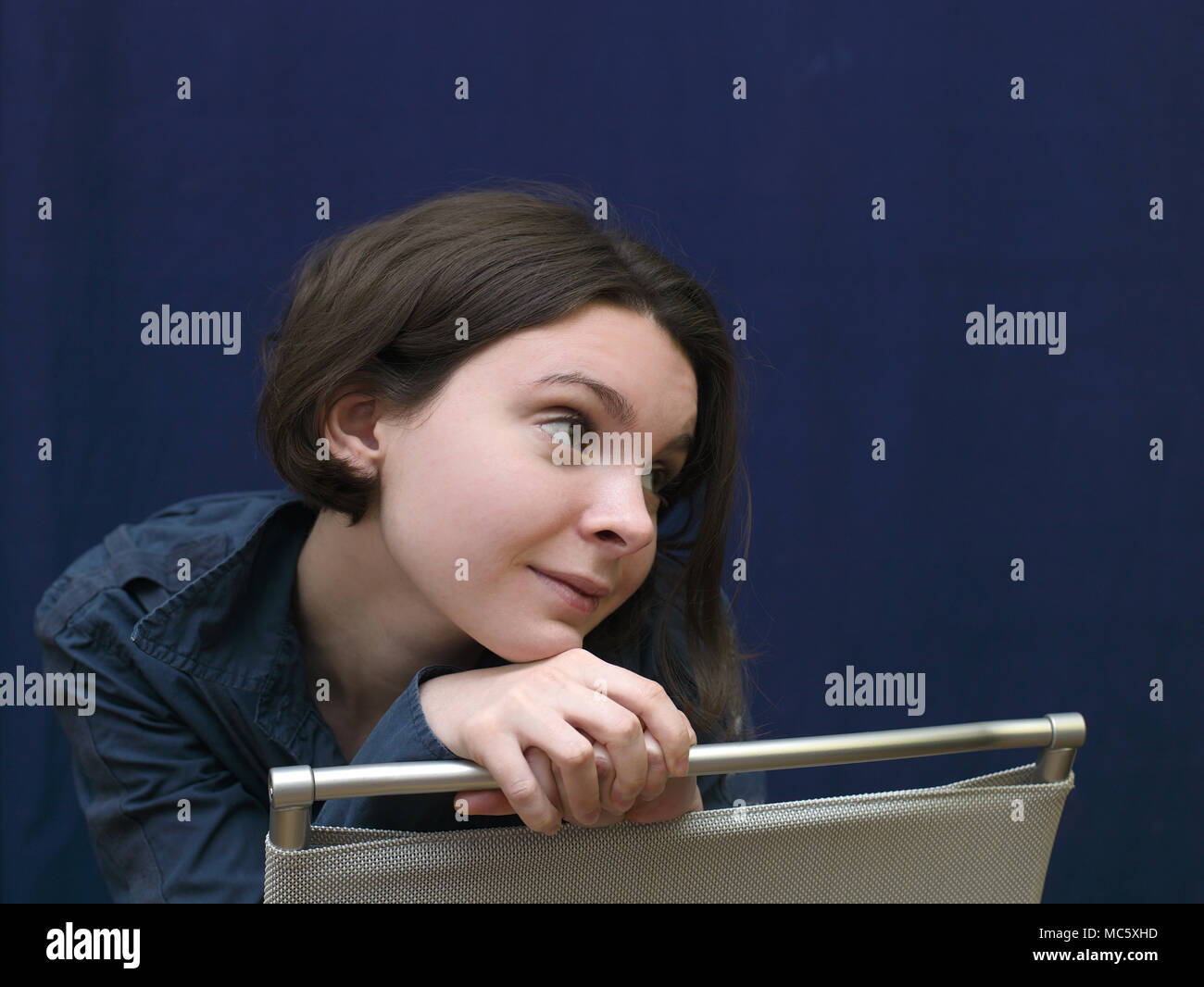 Young female with a distant happy gaze posing on a backward chair Stock ...