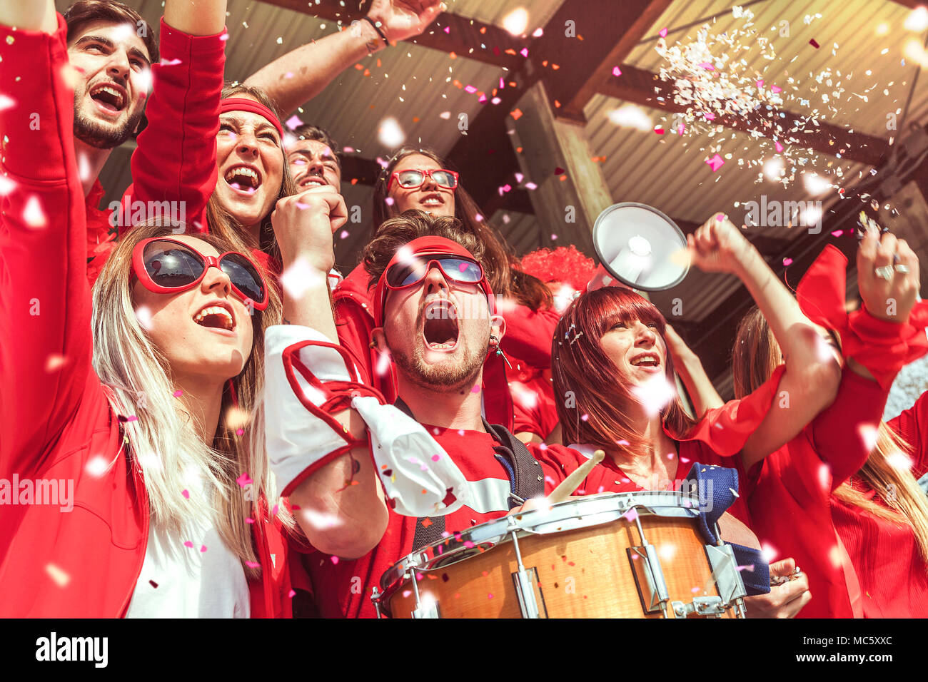 group of fans dressed in red color watching a sports event in the ...
