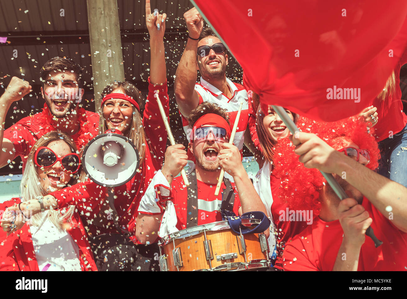 group of fans dressed in red color watching a sports event in the ...