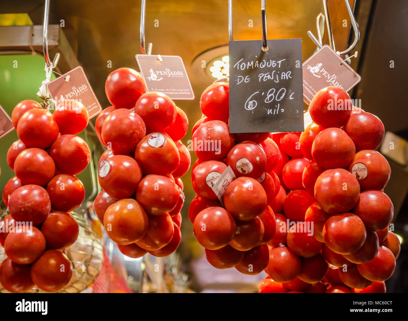Fresh tomatoes hanging form metal hooks at a market stall Stock Photo ...