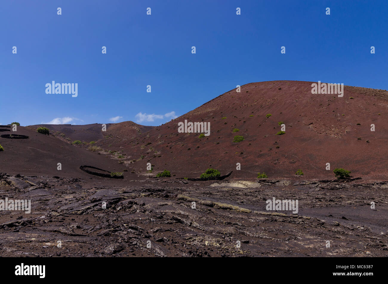 Volcanic hill with a crater seen from the trekking path in Timanfaya ...