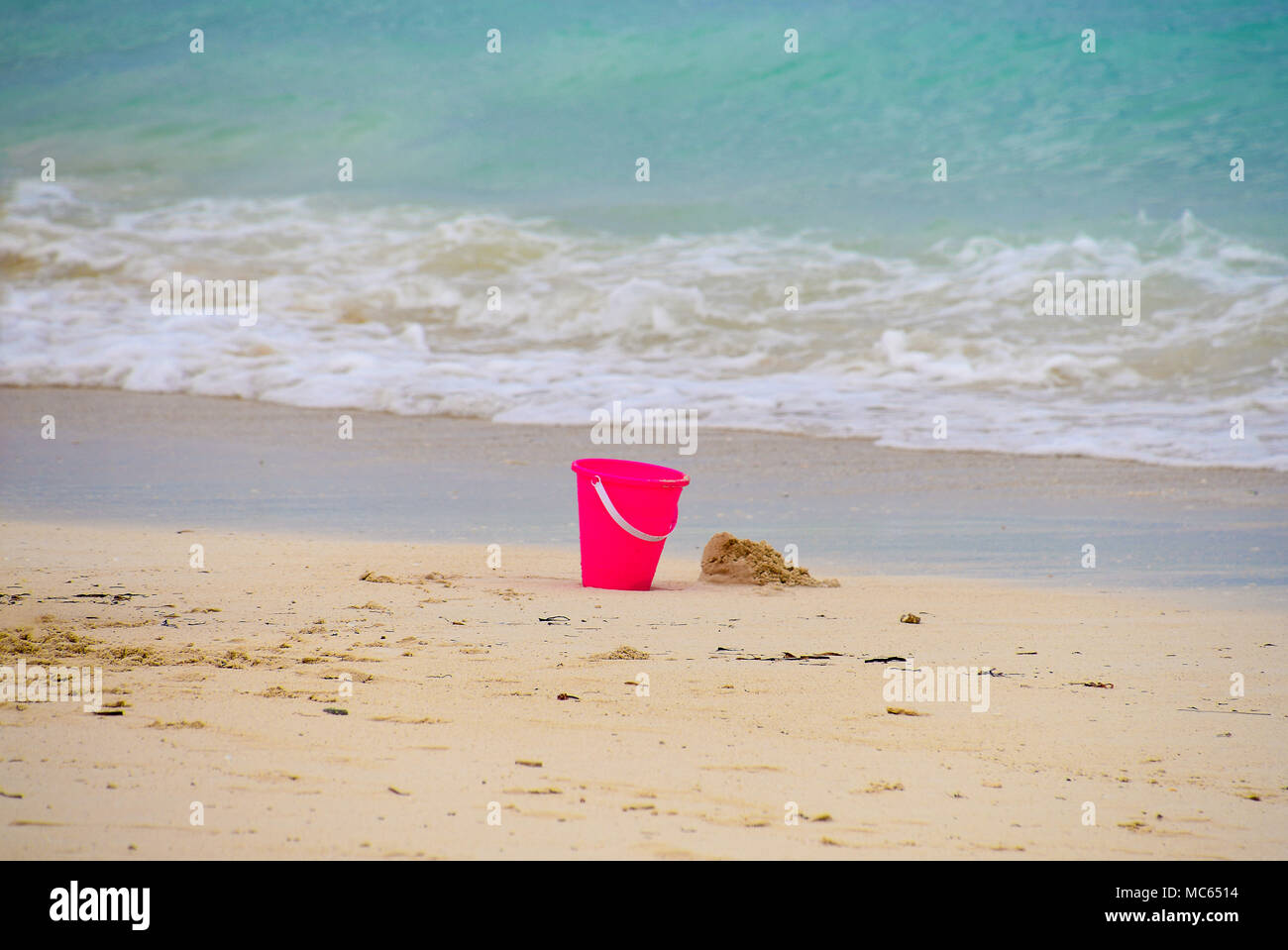 bright pink plastic pail on ocean beach with surf background Stock ...