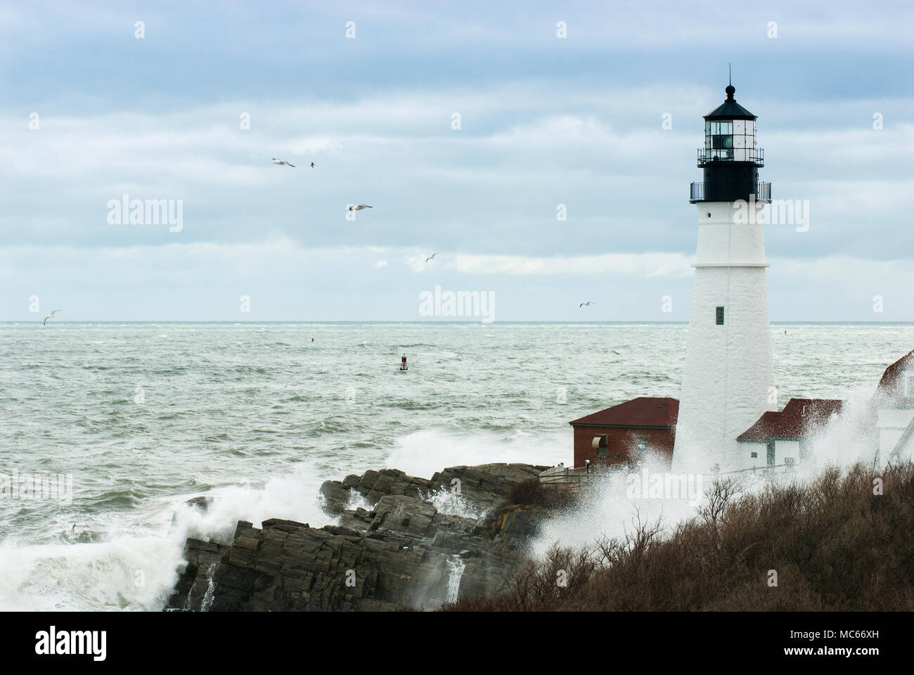 Surf creates huge waves crashing by Portland Head lighthouse as sun ...
