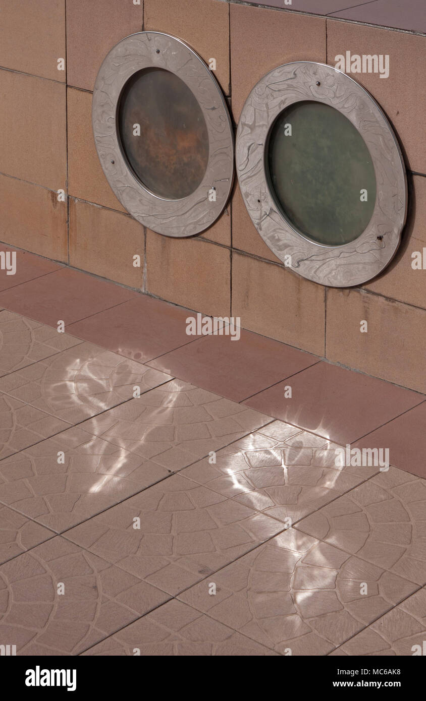 Distorted sunlight reflections on paved path from polished metal ...