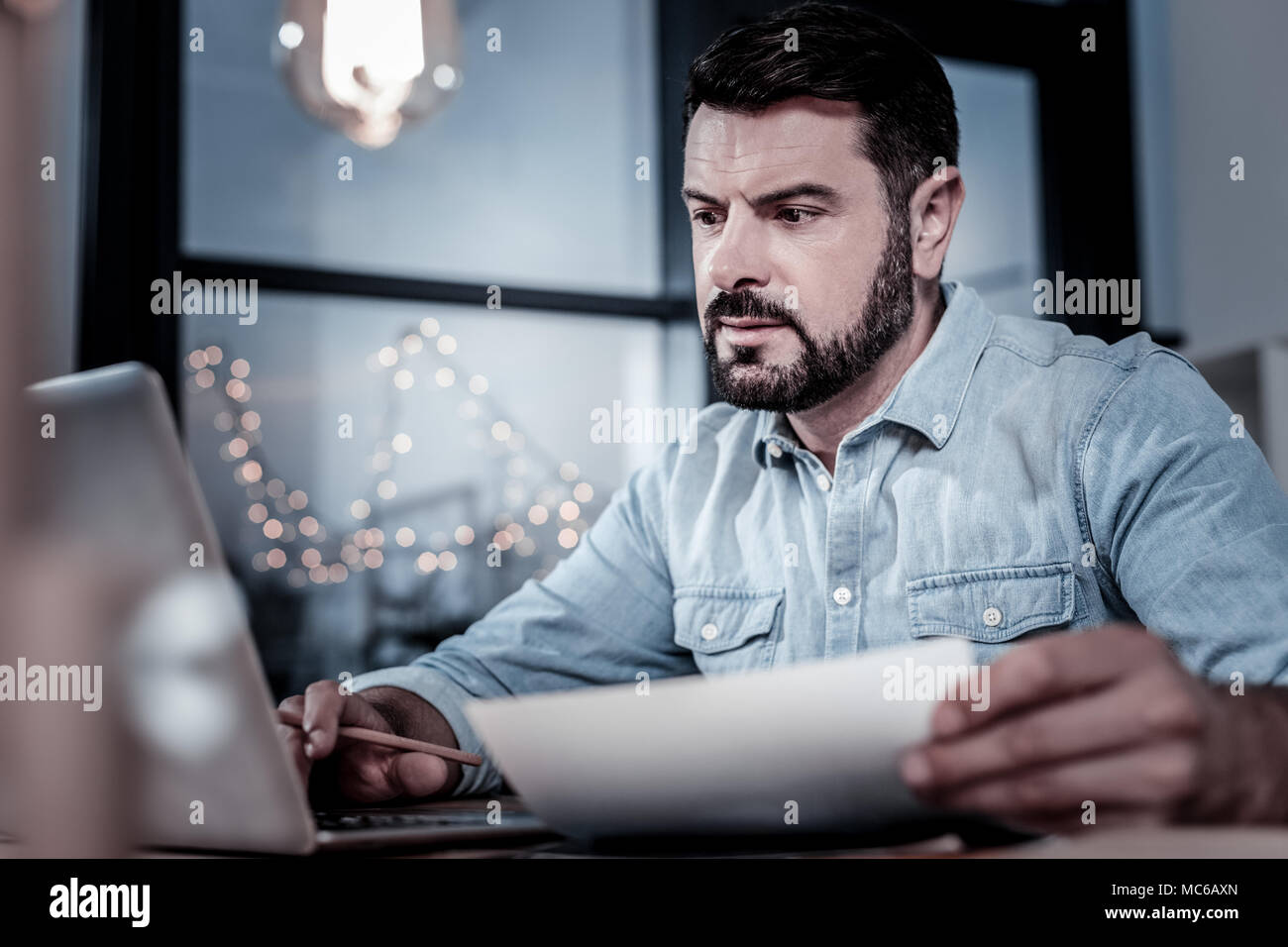 Busy handsome workers holding the document and using his laptop Stock ...