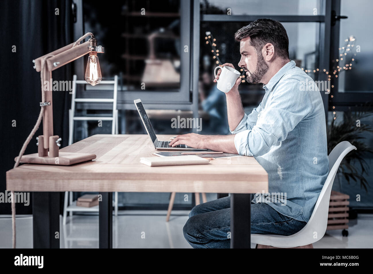 Serious busy man using the laptop and drinking tea Stock Photo - Alamy