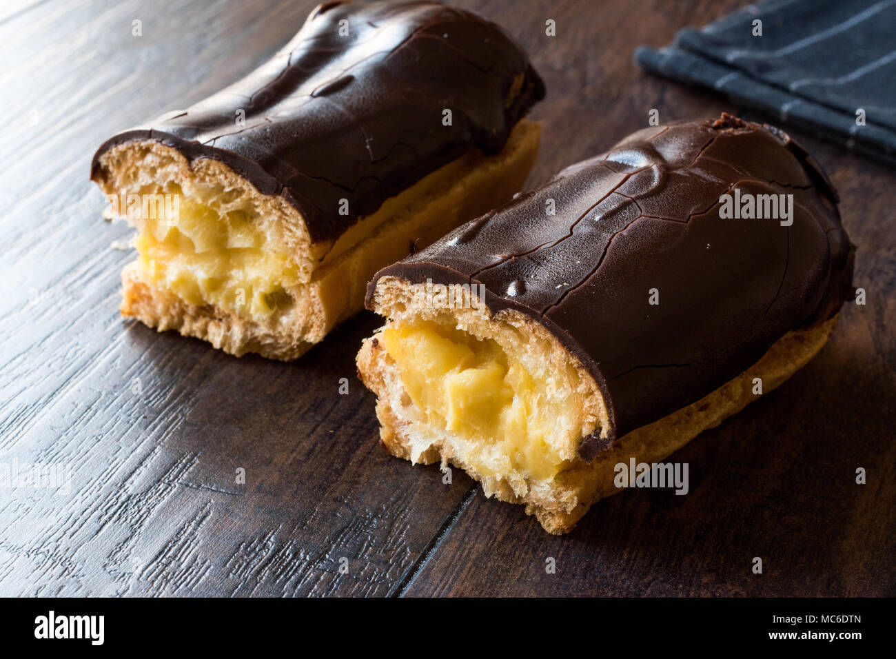 Half Cut Cream Filled Chocolate Eclairs on Dark Wooden Surface. Dessert ...