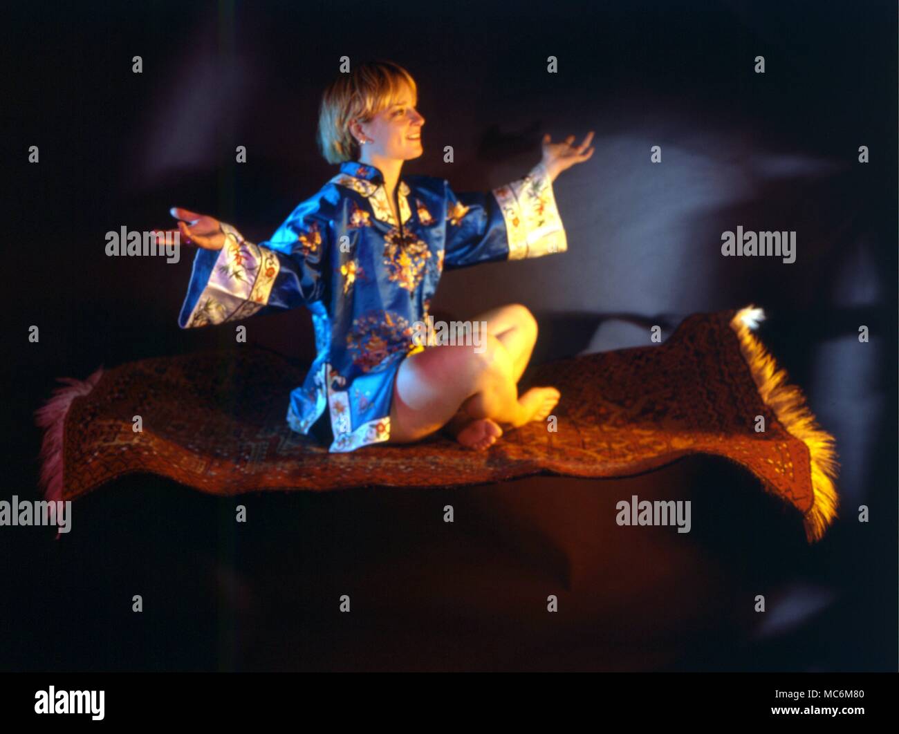 Levitation. Young girl flying, or levitating, on a magic carpet - a ...
