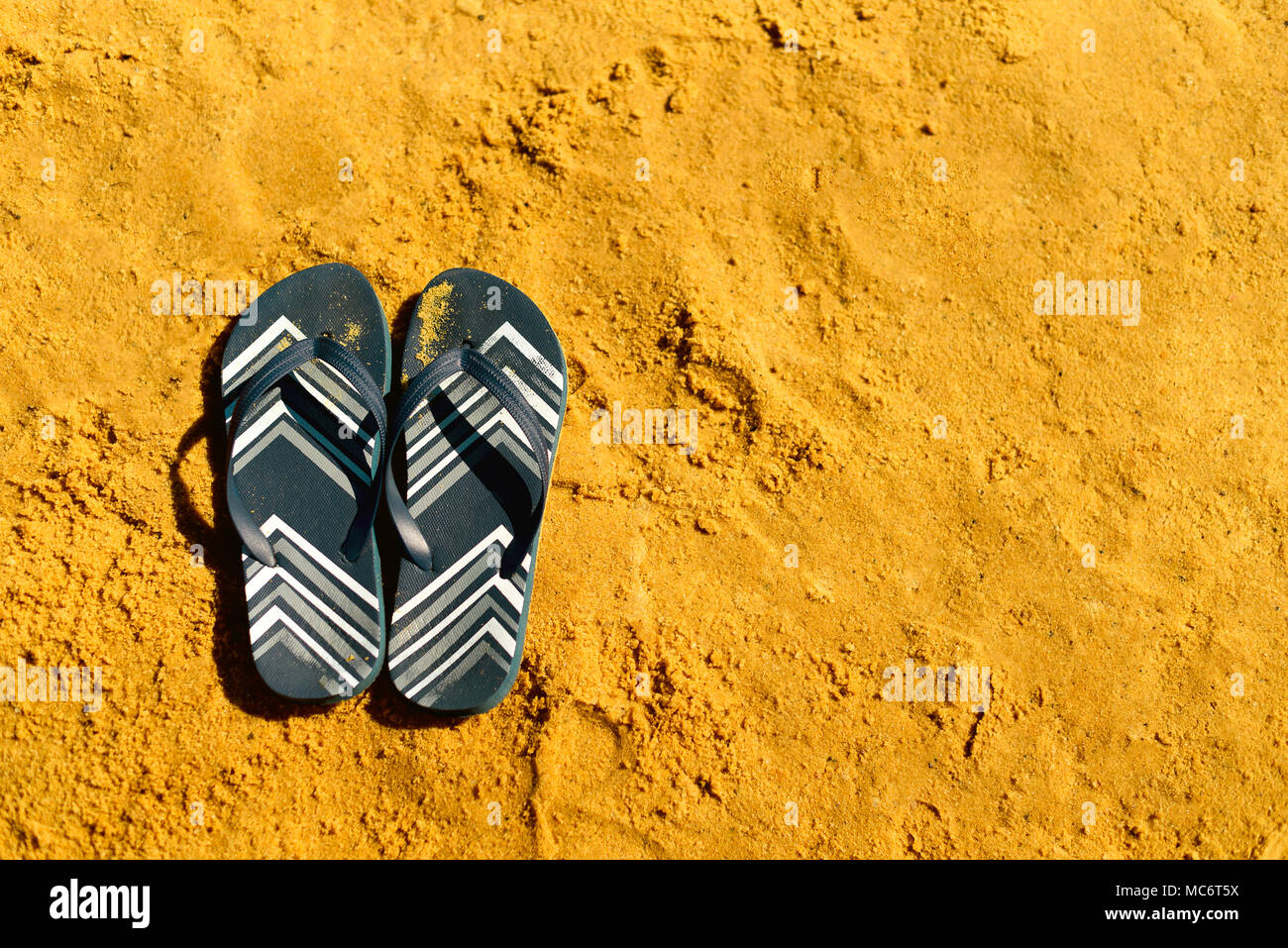 Summer slippers. Navy blue flip flop on yellow sand beach background ...