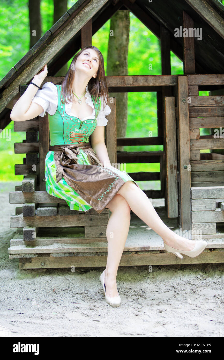young bavarian woman wearing a dirndl sitting at wooden lodge Stock ...