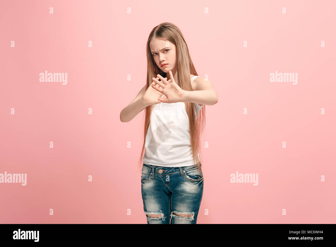 Doubtful pensive teen girl rejecting something against pink background ...