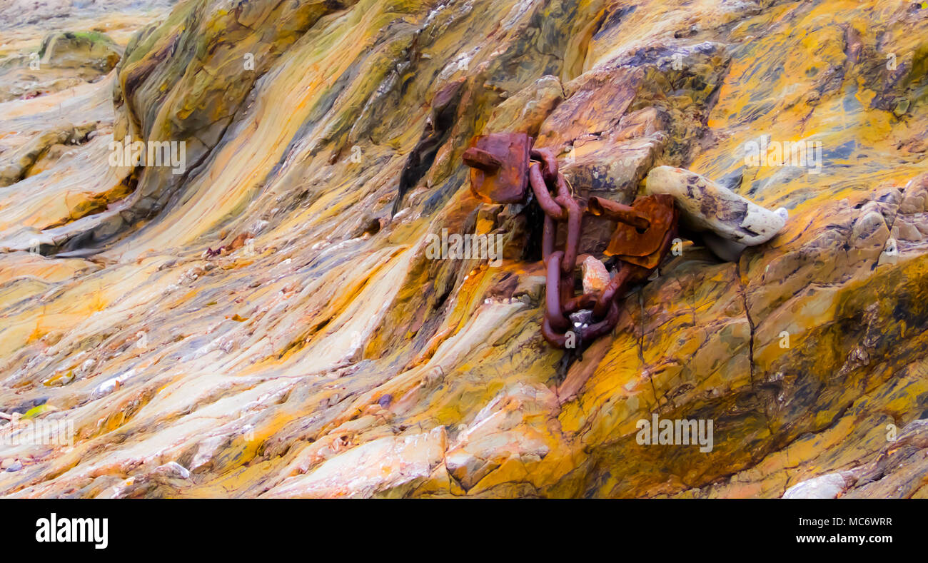 Yellow and gold streaked rocks with old rusty chain link imbedded in ...
